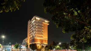 Um hotel moderno com design vertical marcante, várias varandas e fachada bem iluminada.