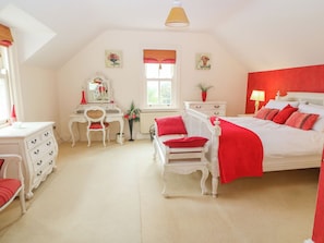 Um quarto com cama, escrivaninha, cadeira, cômoda e janela.