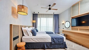 Quarto de hotel moderno com uma cama grande, ventoinha no teto, televisão e aparador de madeira.