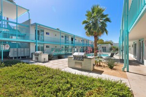 Um motel com piscina, churrasqueira externa e área de varanda coberta.