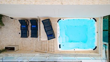 Uma área de piscina no terraço com duas espreguiçadeiras e uma banheira de hidromassagem.