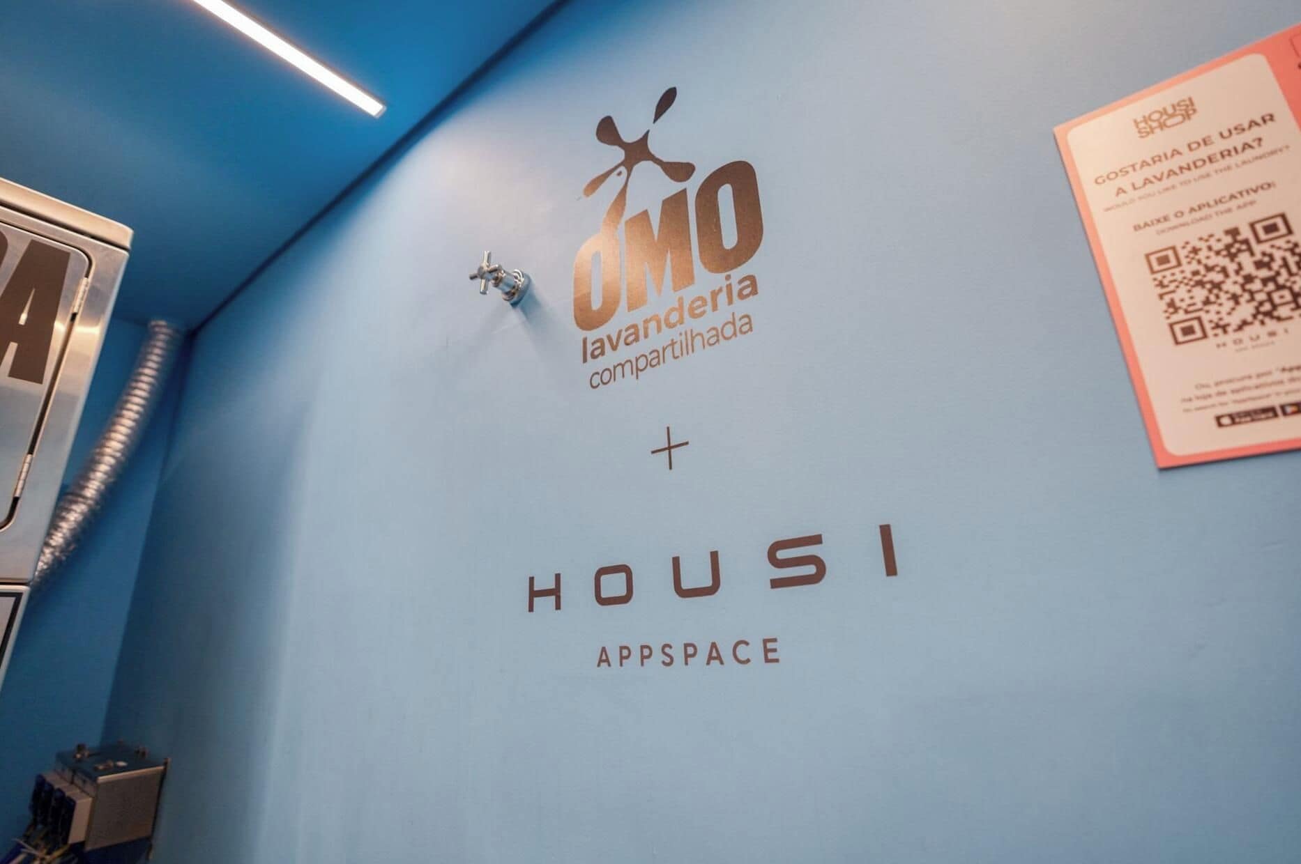 Paredes com o logotipo e texto para 'OMO lavanderia compartilhada' e 'HOUSI APPSPACE'.