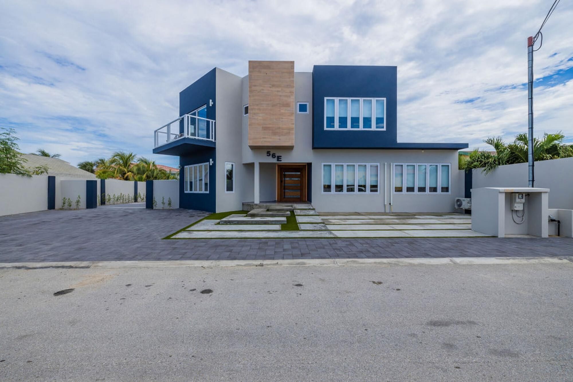 Uma casa moderna de dois andares com telhado plano, varanda e garagem.