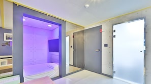 Quarto de hotel moderno com cama, banheiro com espelho e porta com fechadura.