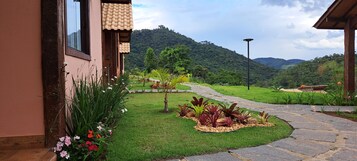 Uma trilha conduz a uma casa com jardim e vista para uma montanha.