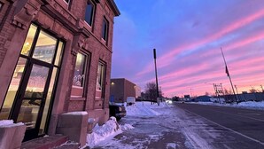 A brick building with a sign reading "ZENITH BUREAUCRATIC" and a parking lot with snow on the ground.