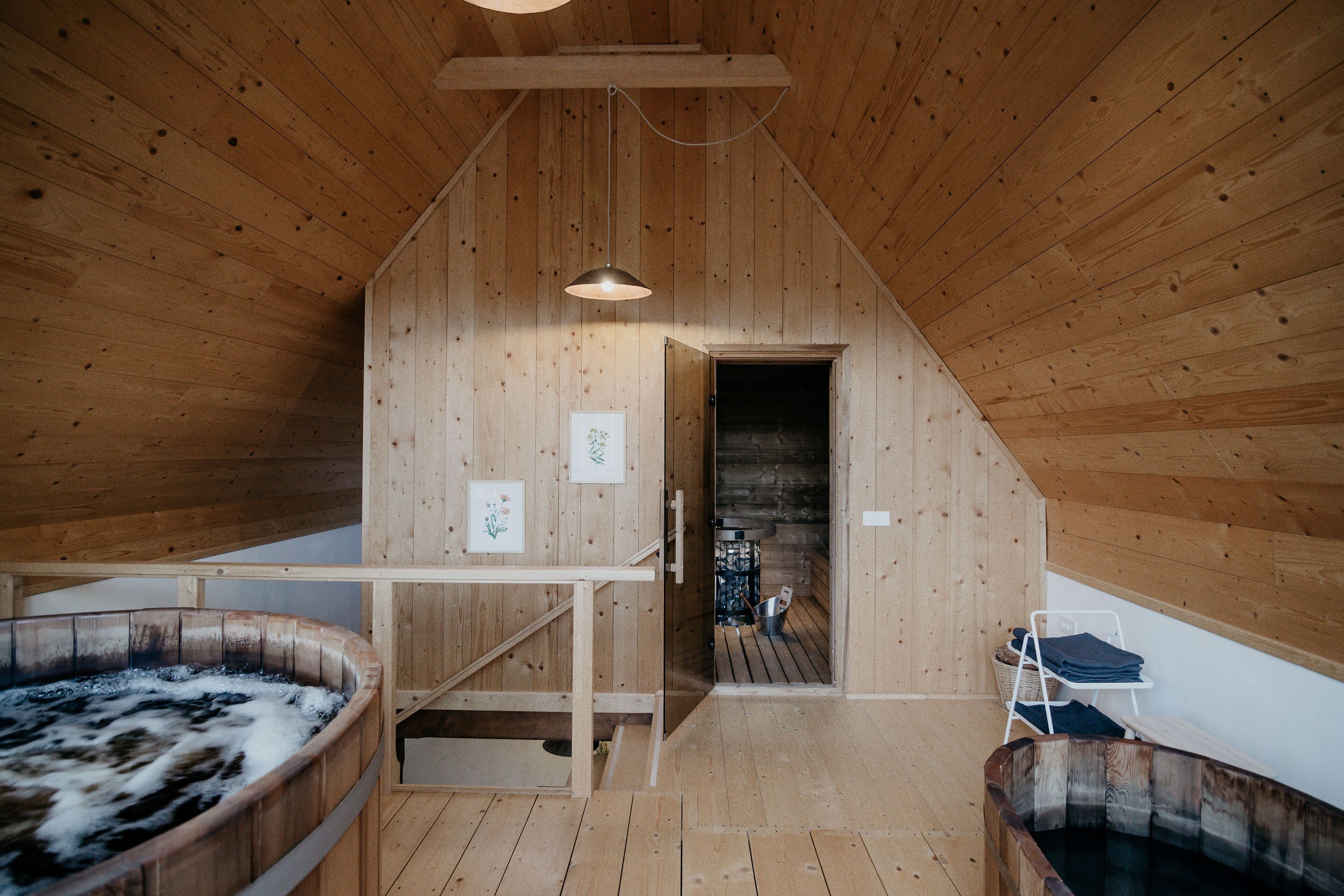 Uma cabana de madeira com duas banheiras de hidromassagem, uma escadaria e uma porta que dá para um banheiro.