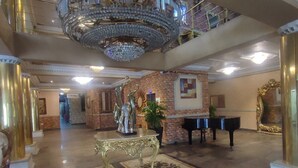 Um hall imponente com um candelabro, um piano e uma estátua.