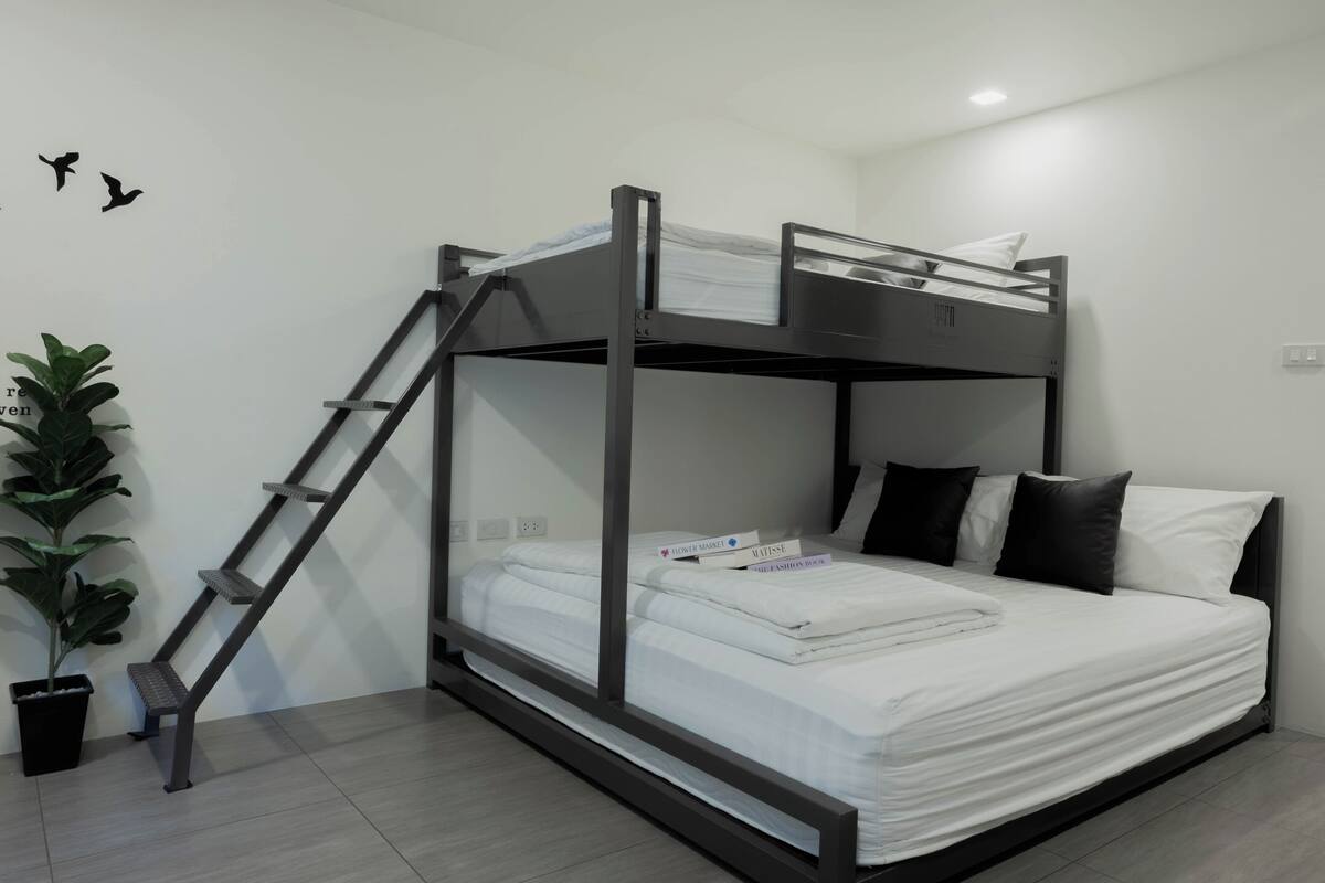 Uma cama beliche com escada, roupa de cama branca e uma planta em vaso.