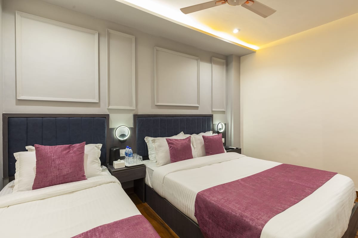 Quarto de hotel com duas camas, cada uma com cabeceira, mesas de cabeceira e luminárias.