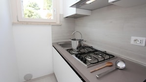 Uma cozinha moderna com fogão a gás, uma panela, uma colher de pau e uma concha sobre o balcão.