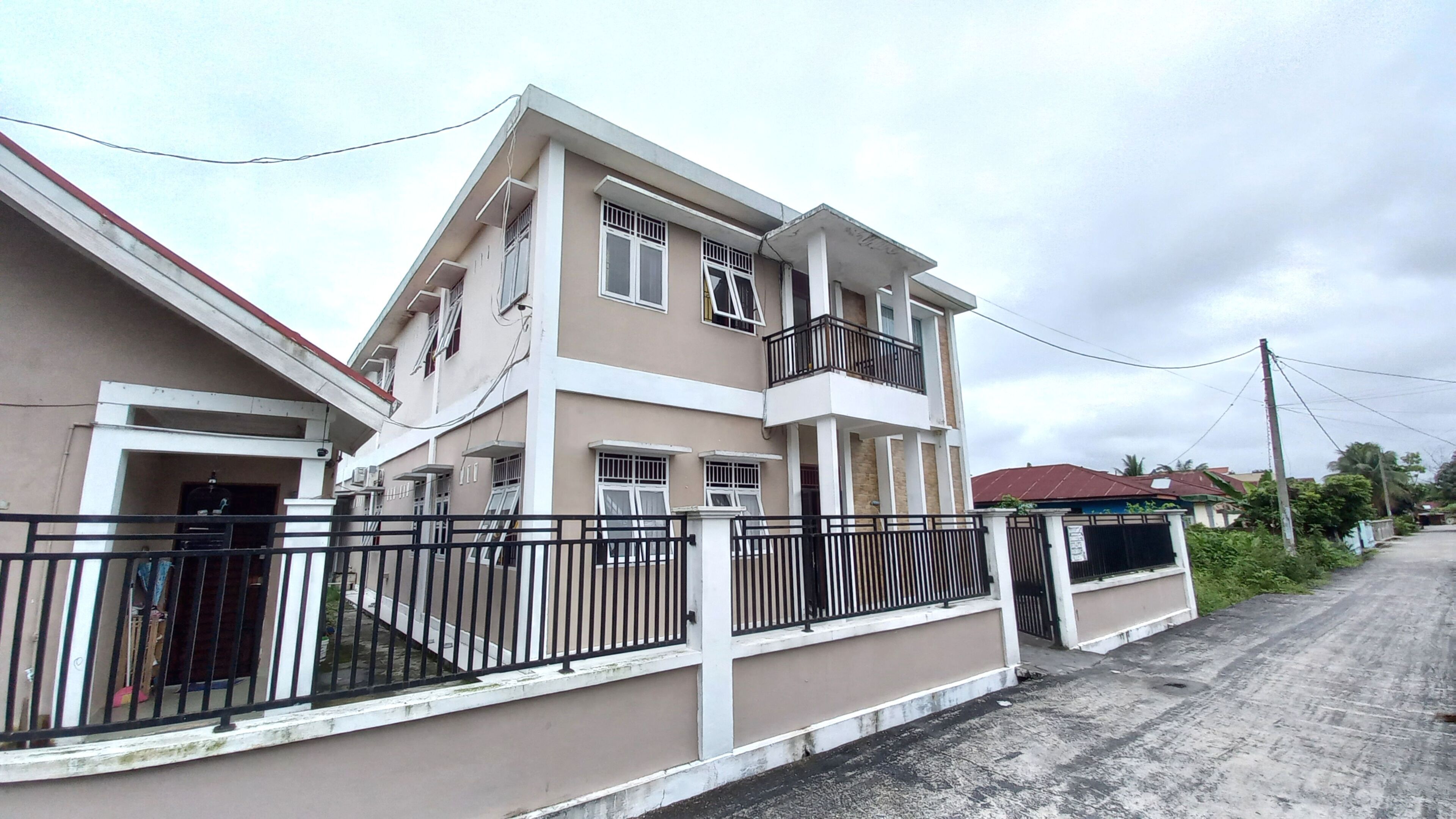 Edifício residencial com vários andares, varanda no andar superior, entrada com portão e escada visível que leva à entrada.