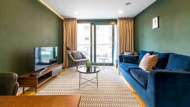 Uma sala de estar moderna com TV, sofá e mesa de centro.