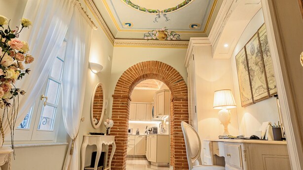 Um corredor luxuoso com teto decorativo, arco de tijolos e mobiliário elegante.