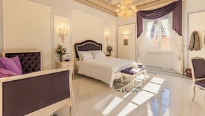 Um quarto espaçoso com uma cama grande, um espaço de estar e um candelabro.