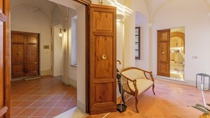 Um corredor amplo com portas de madeira e uma cadeira.