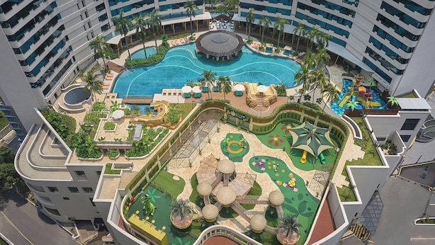 Hotel com piscina central, várias varandas e área de recreação infantil.