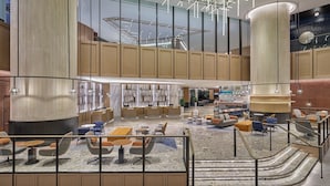 Um hall amplo com área de estar central, escadaria e teto alto com luminárias modernas.