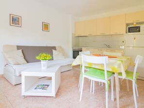 Um espaço de estar compacto com sofá, mesa de jantar pequena e cozinha.