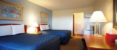 Quarto de hotel com duas camas, uma escrivaninha, uma cadeira, um abajur, uma televisão e um quadro na parede.
