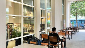 Café com mesas ao ar livre, grandes janelas e placa visível da Wayne's Coffee.