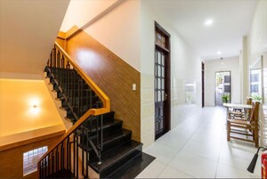 Interior moderno com escada de madeira, área de refeições e porta com painel de vidro decorativo.