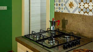 Cozinha com fogão a gás, armários de madeira e painel decorado.