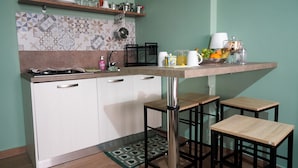 Uma cozinha com bancada, pia, fogão e prateleira com louças e potes.