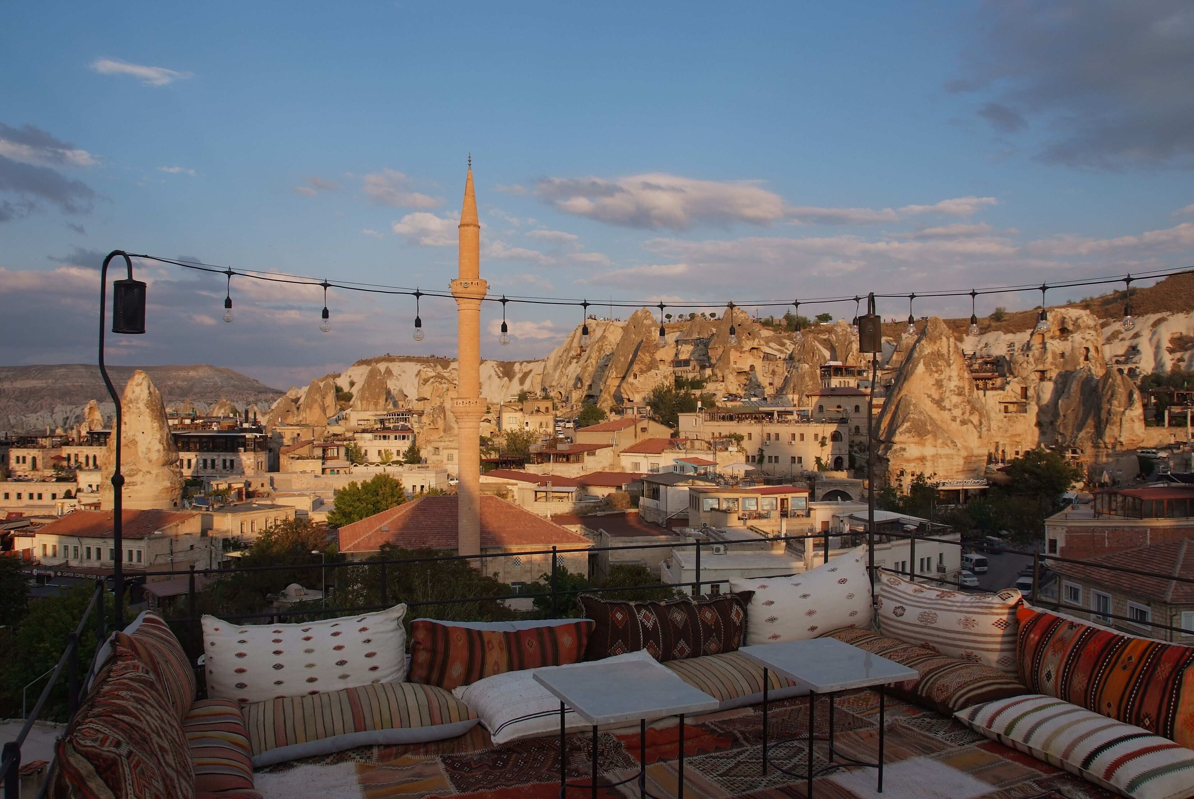 Terraço no telhado com vista para uma cidade histórica, apresentando um minarete e arquitetura tradicional.