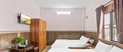 Quarto de hotel com duas camas, uma escrivaninha, uma cadeira, uma televisão e uma janela com cortinas.