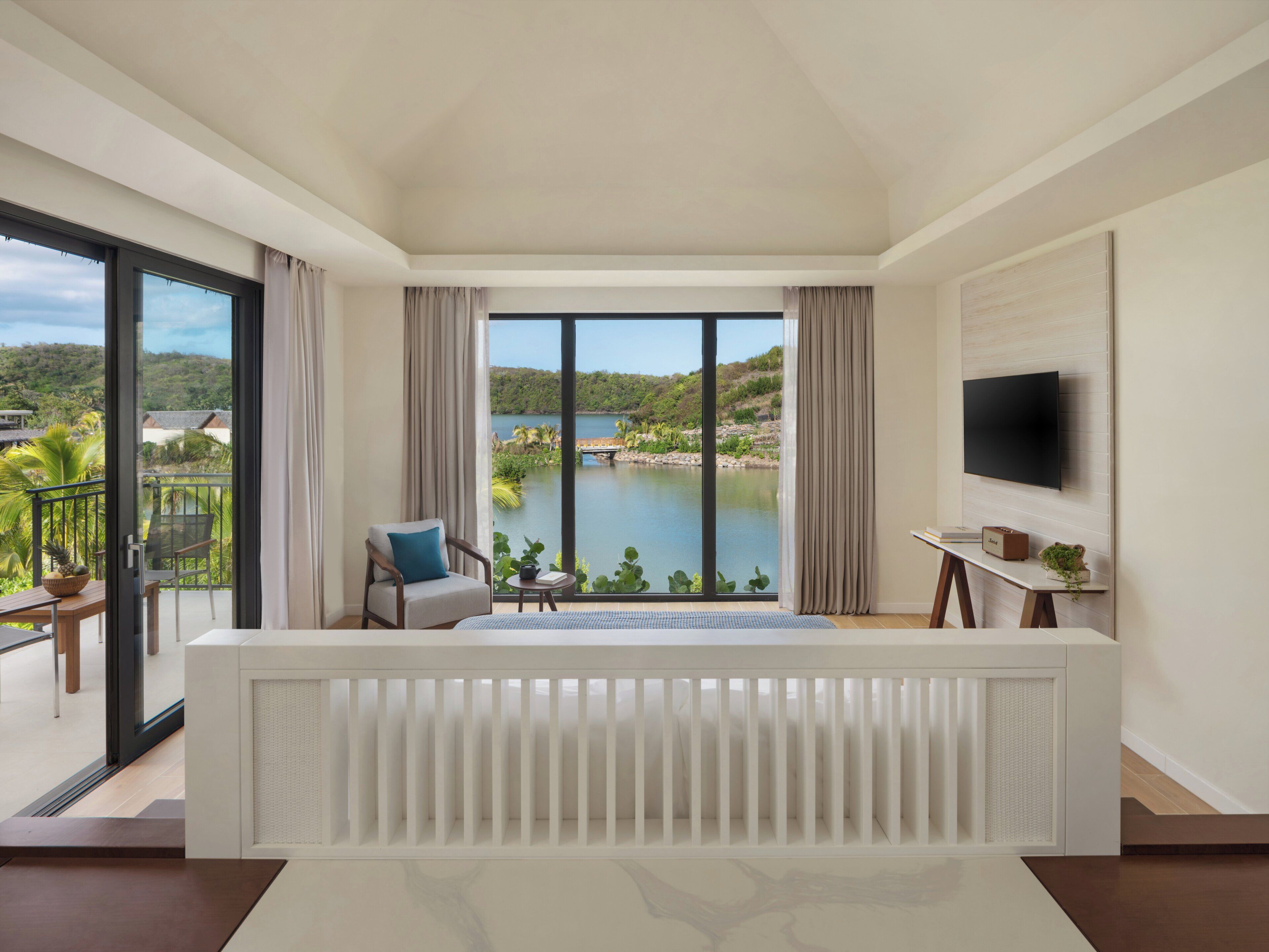 Quarto moderno com vista para um lago, televisão e área de estar também com vista.