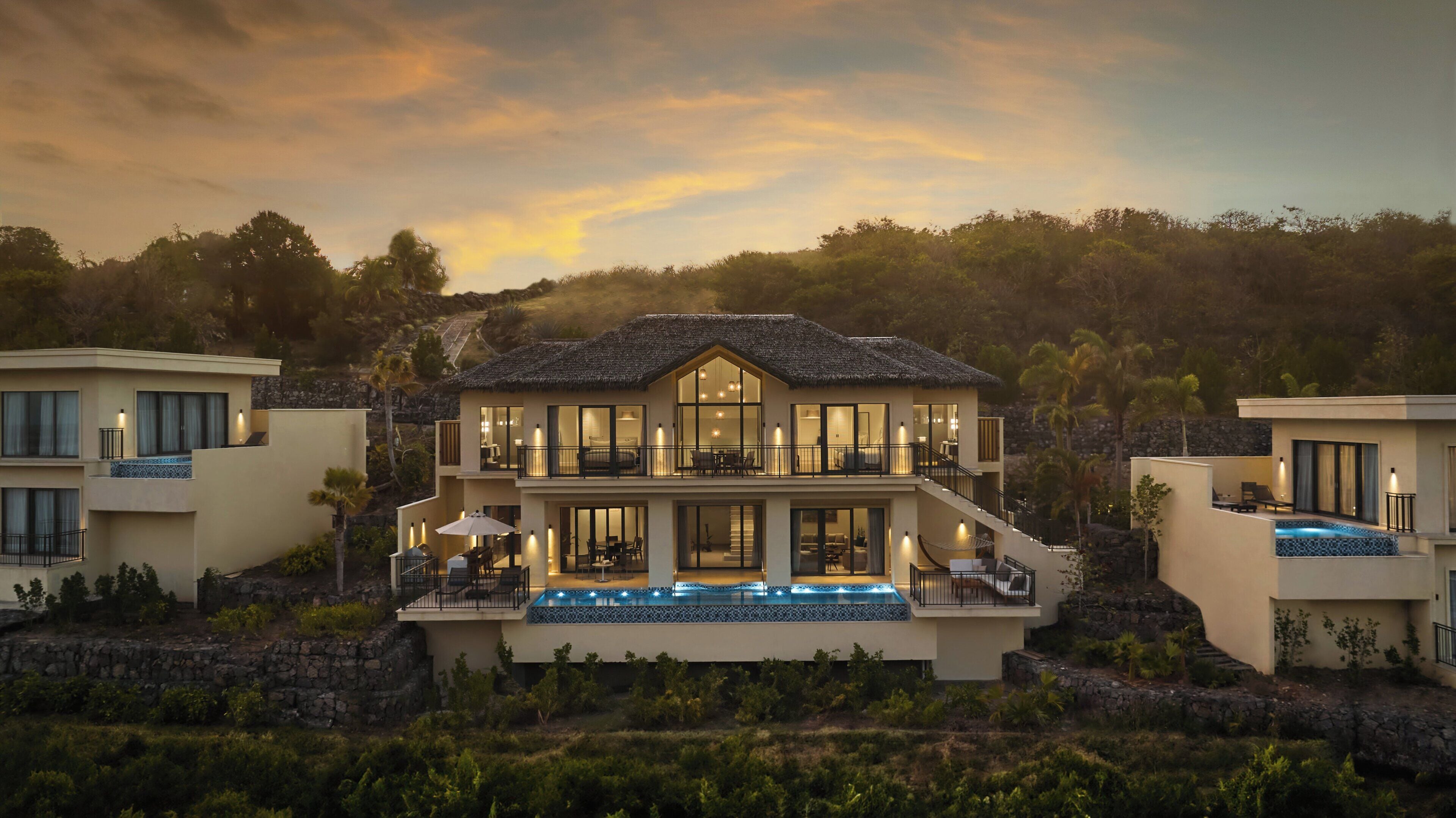 Uma casa de dois andares com uma varanda grande, piscina e vista para a paisagem ao redor.