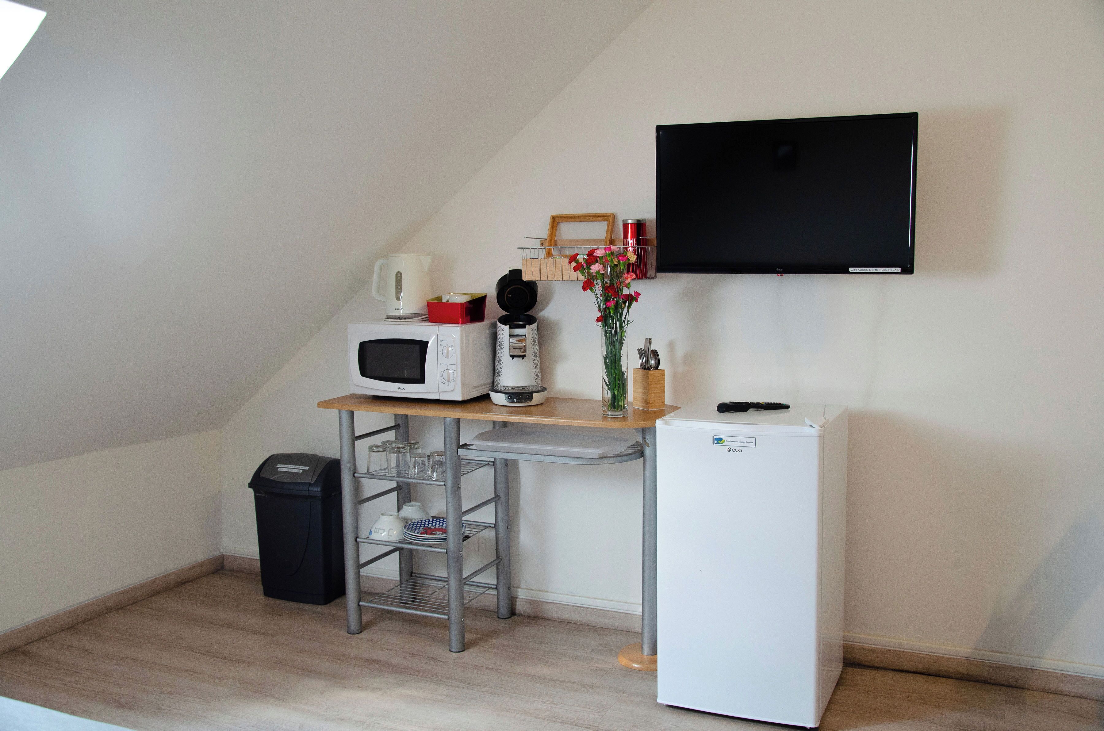 Uma cozinha compacta equipada com micro-ondas, cafeteira e um frigorífico pequeno.