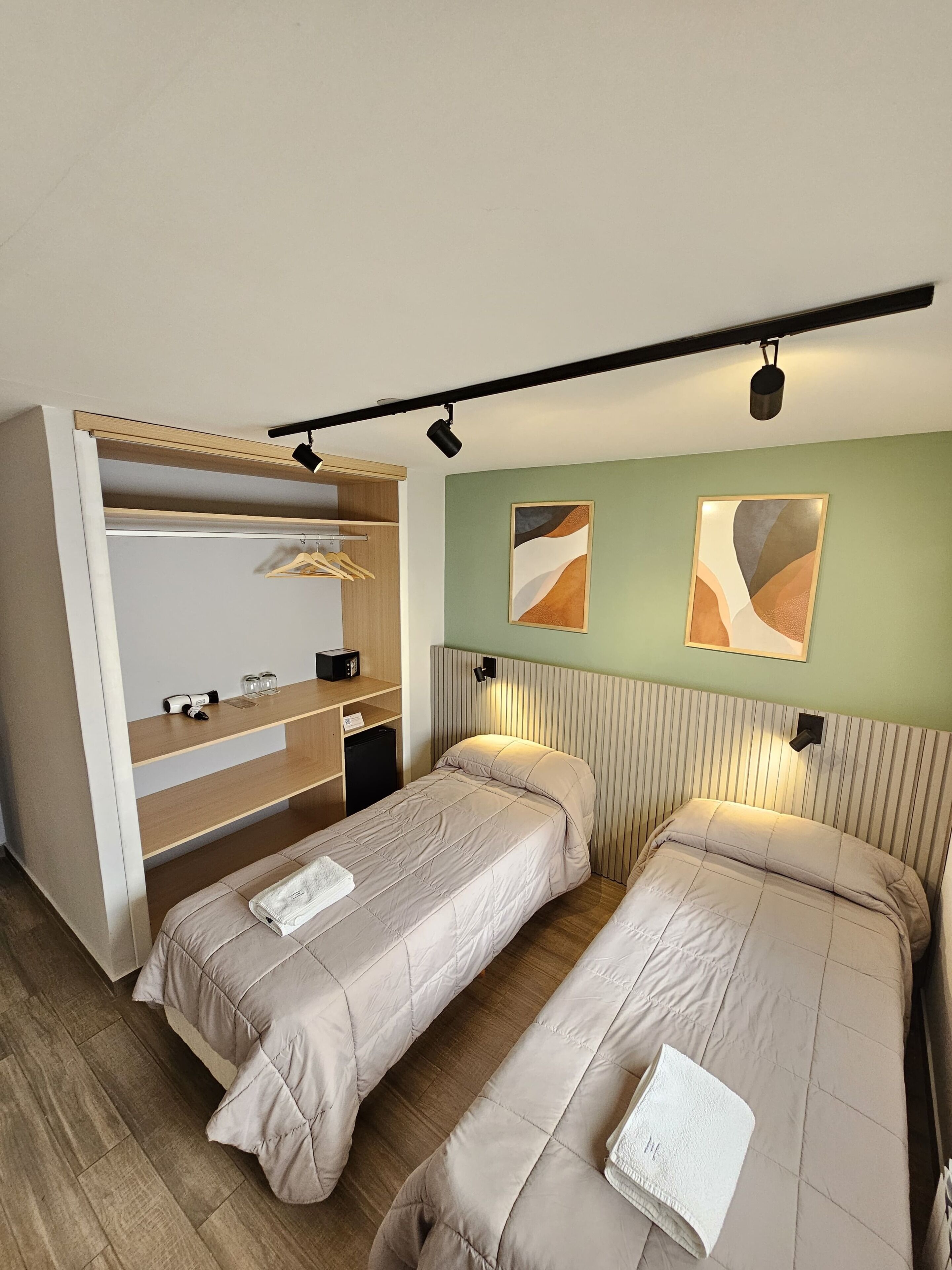 Quarto com duas camas, armário embutido e obra de arte na parede.