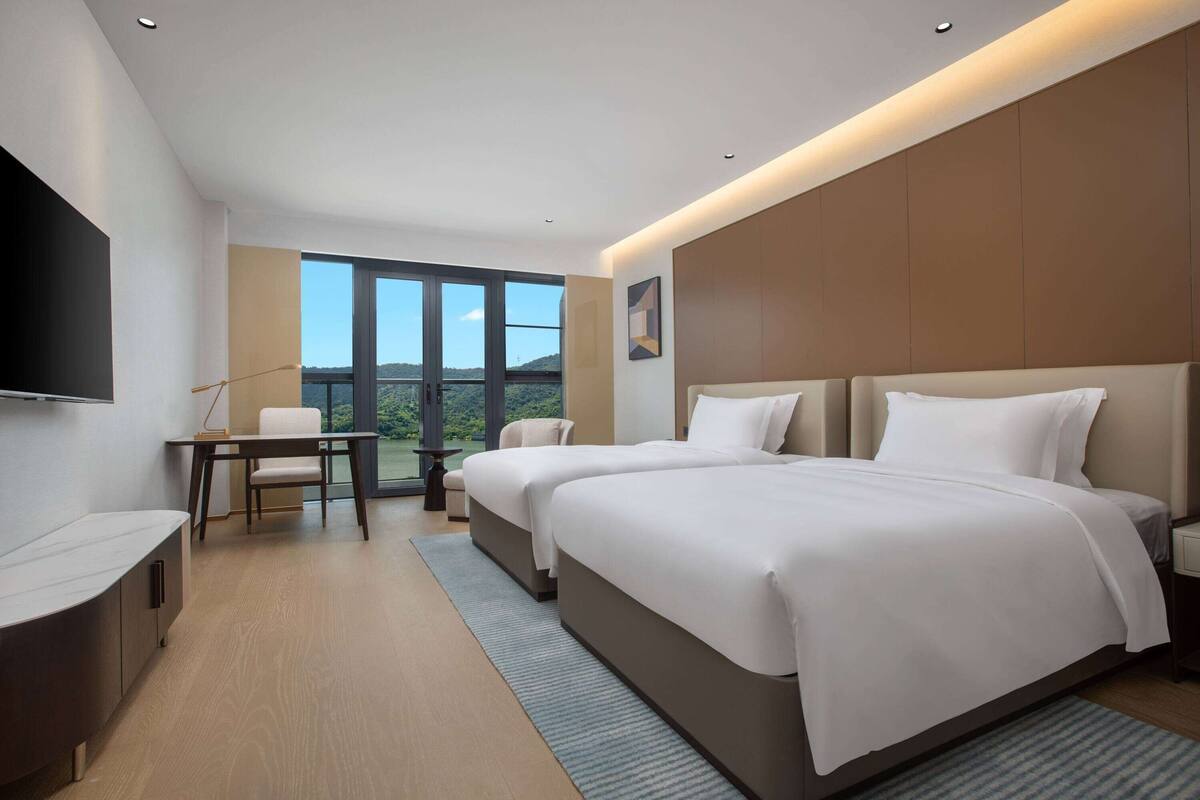 Quarto de hotel moderno com uma cama grande, uma escrivaninha e uma televisão.