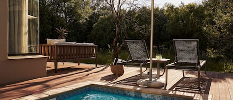 Uma piscina com deck de madeira, cadeiras de sol e uma mesa.