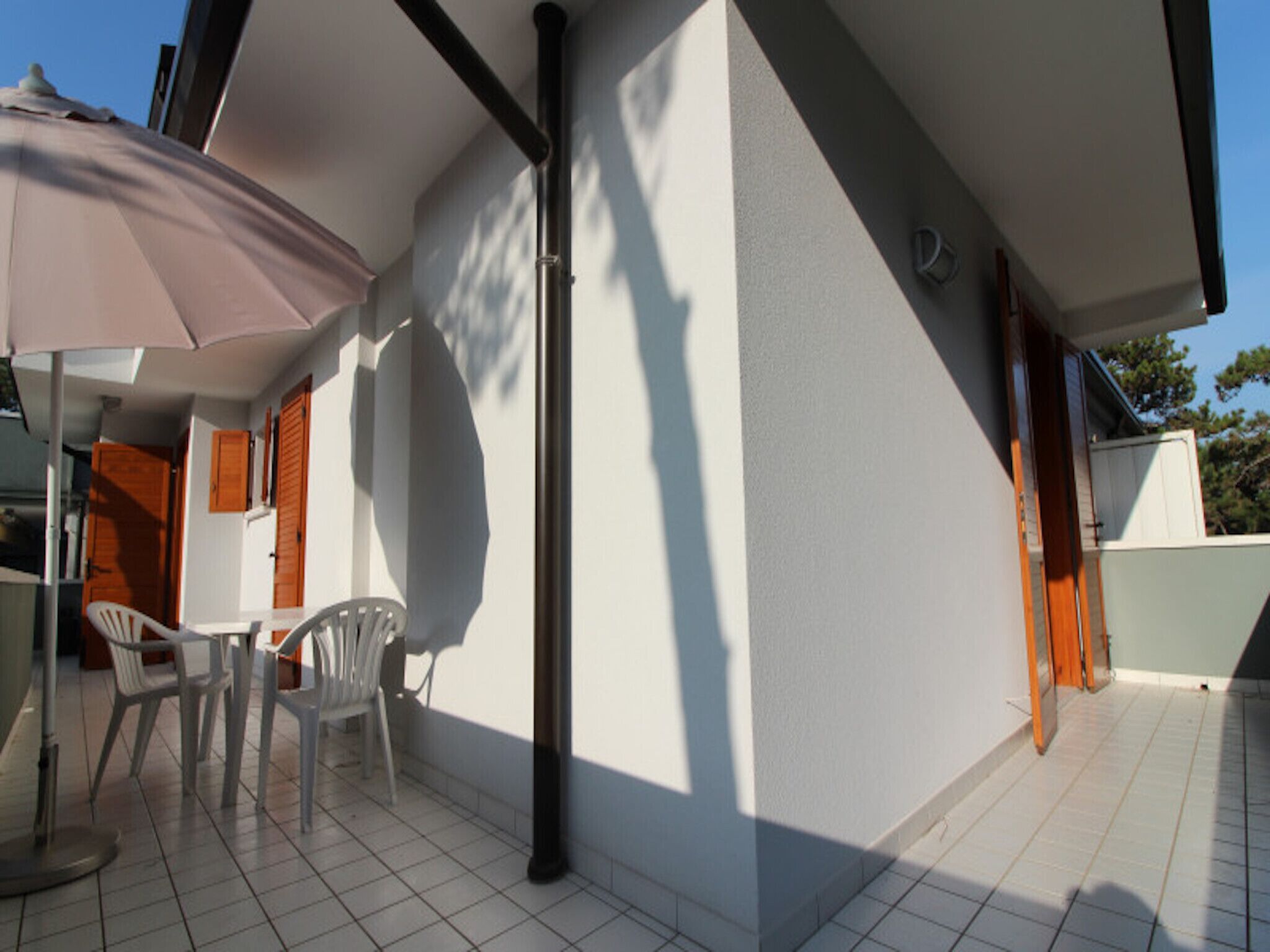Um pátio com mesa, cadeiras, ventilador de teto e janela.