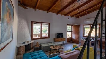 Uma sala de estar ampla com lareira, televisão e escada que dá acesso a outro andar.