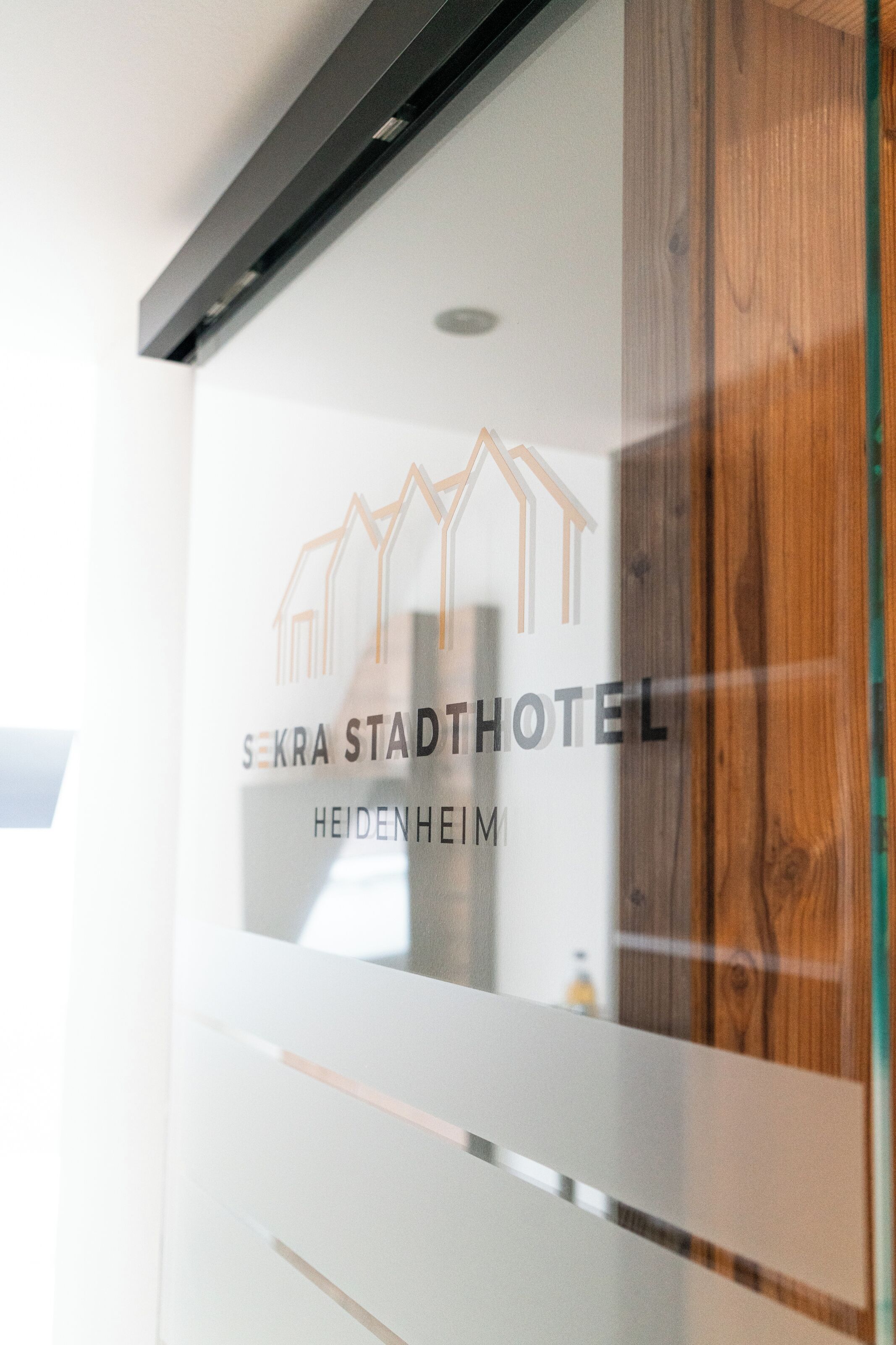 Uma porta de vidro com o logotipo e o nome "Sekra Stadthotel" e "Heidenheim" visíveis.