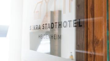 Uma porta de vidro com o logotipo e o nome "Sekra Stadthotel" e "Heidenheim" visíveis.
