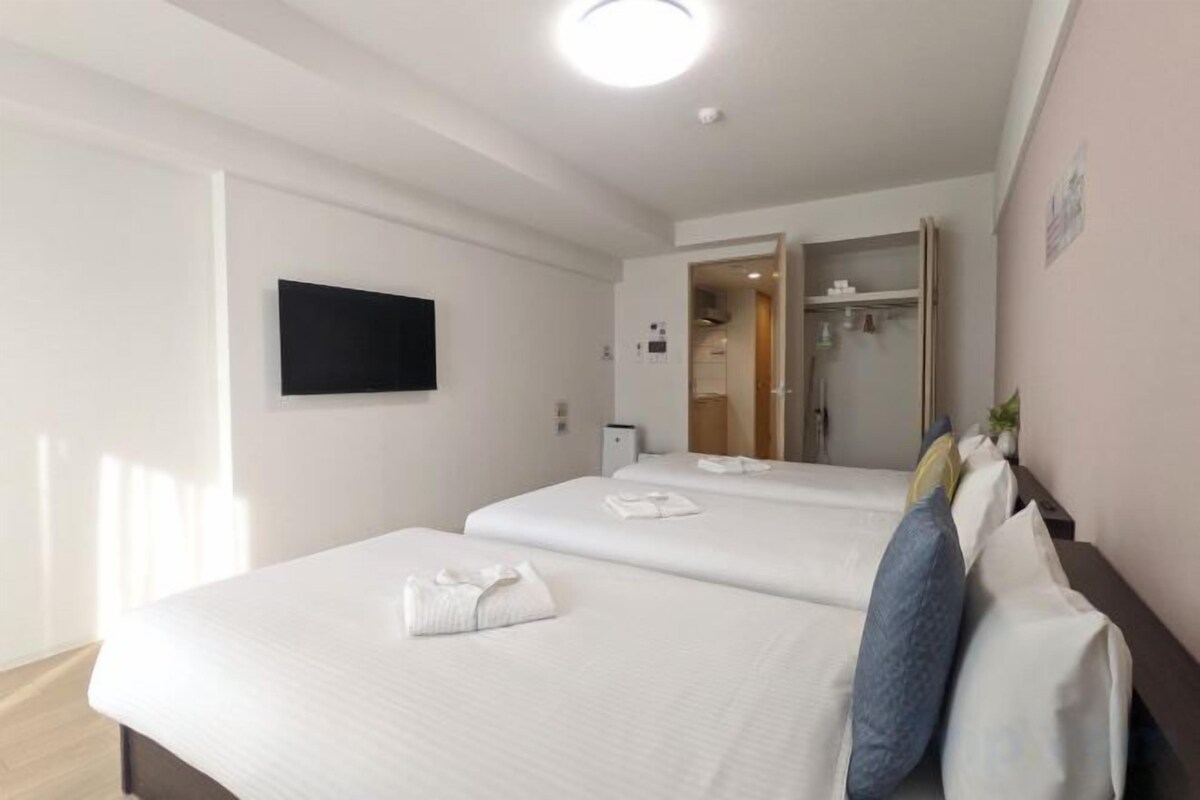 Quarto de hotel com duas camas, televisão de tela plana e banheiro visível por uma porta aberta.