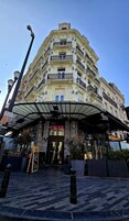 Um edifício de vários andares com entrada coberta e placa indicando 'PIECE Cafe-Resto-Bar'.