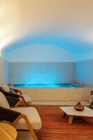 Um spa moderno com uma banheira de hidromassagem grande, assentos confortáveis e um vaso decorativo sobre uma mesa.
