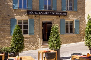 Um edifício de pedra com uma placa que diz "HOTEL LA MÈRE GERMAINE".