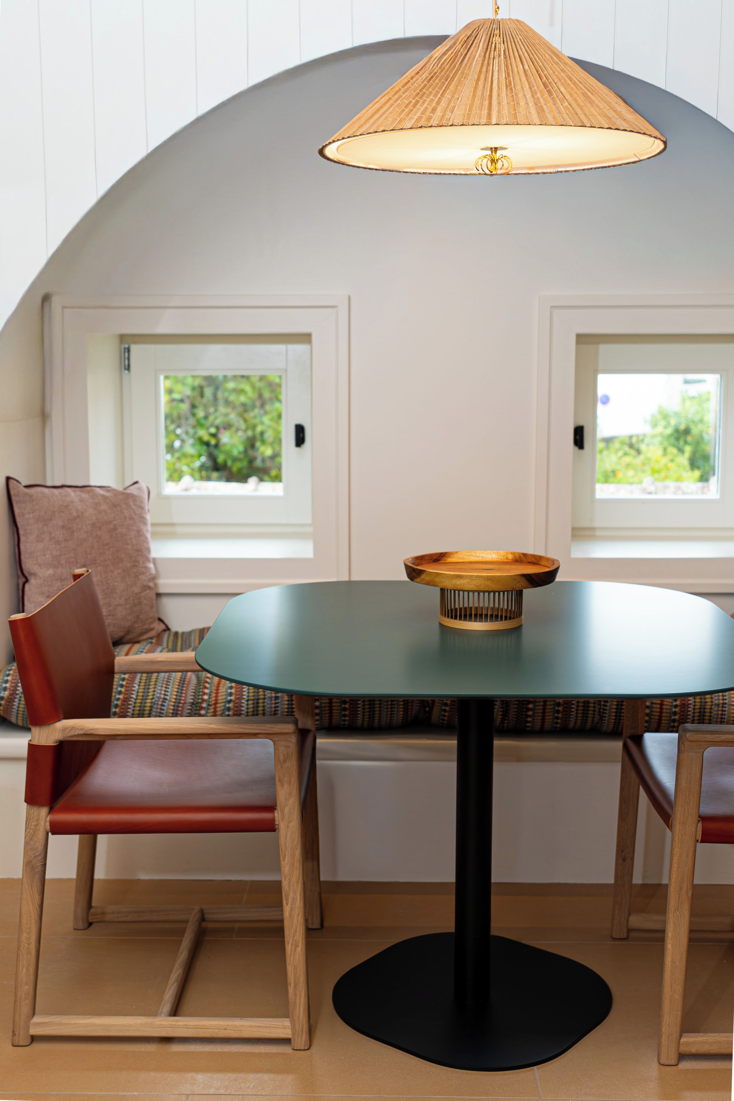Uma área de refeições com uma mesa redonda, duas cadeiras, um banco e um lustre.