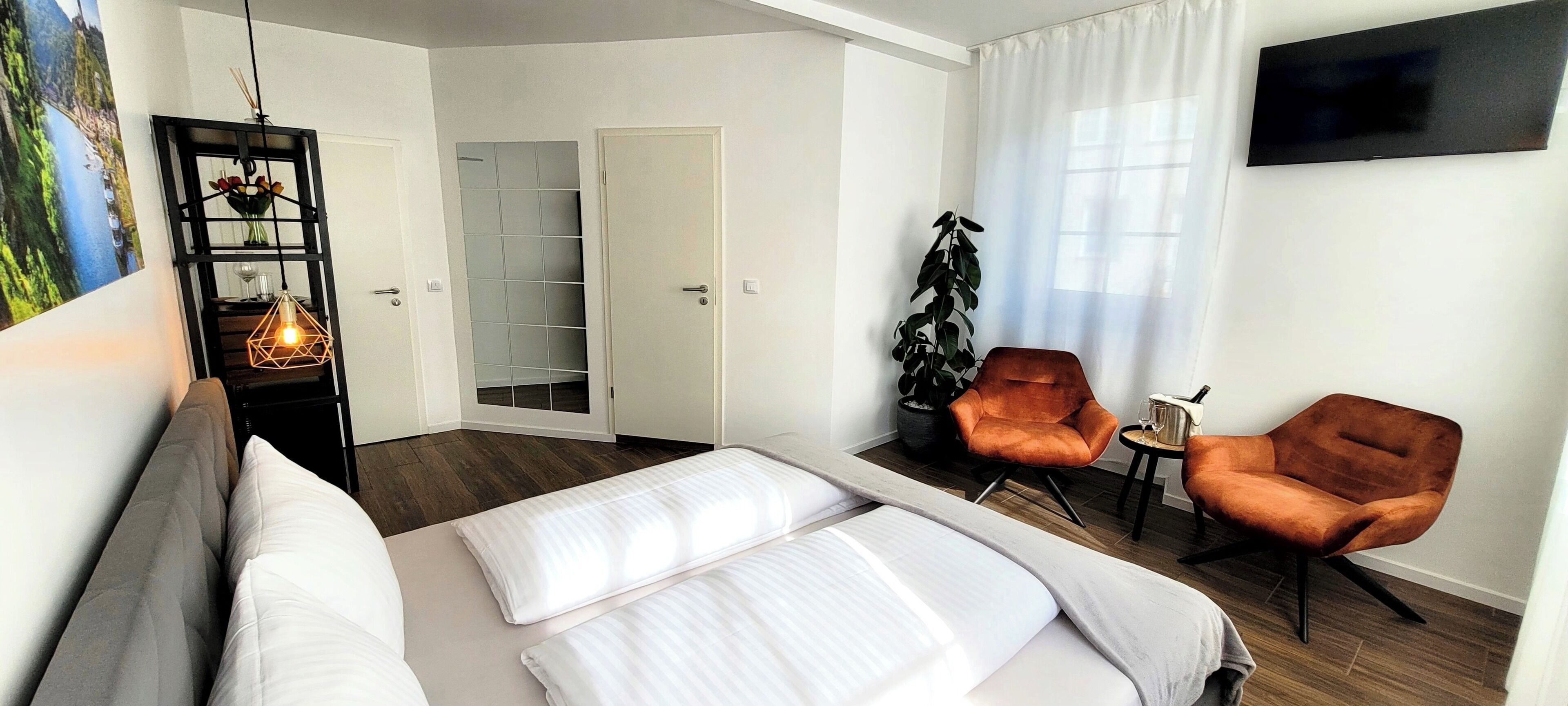 Quarto com cama, guarda-roupa, televisão e duas cadeiras.