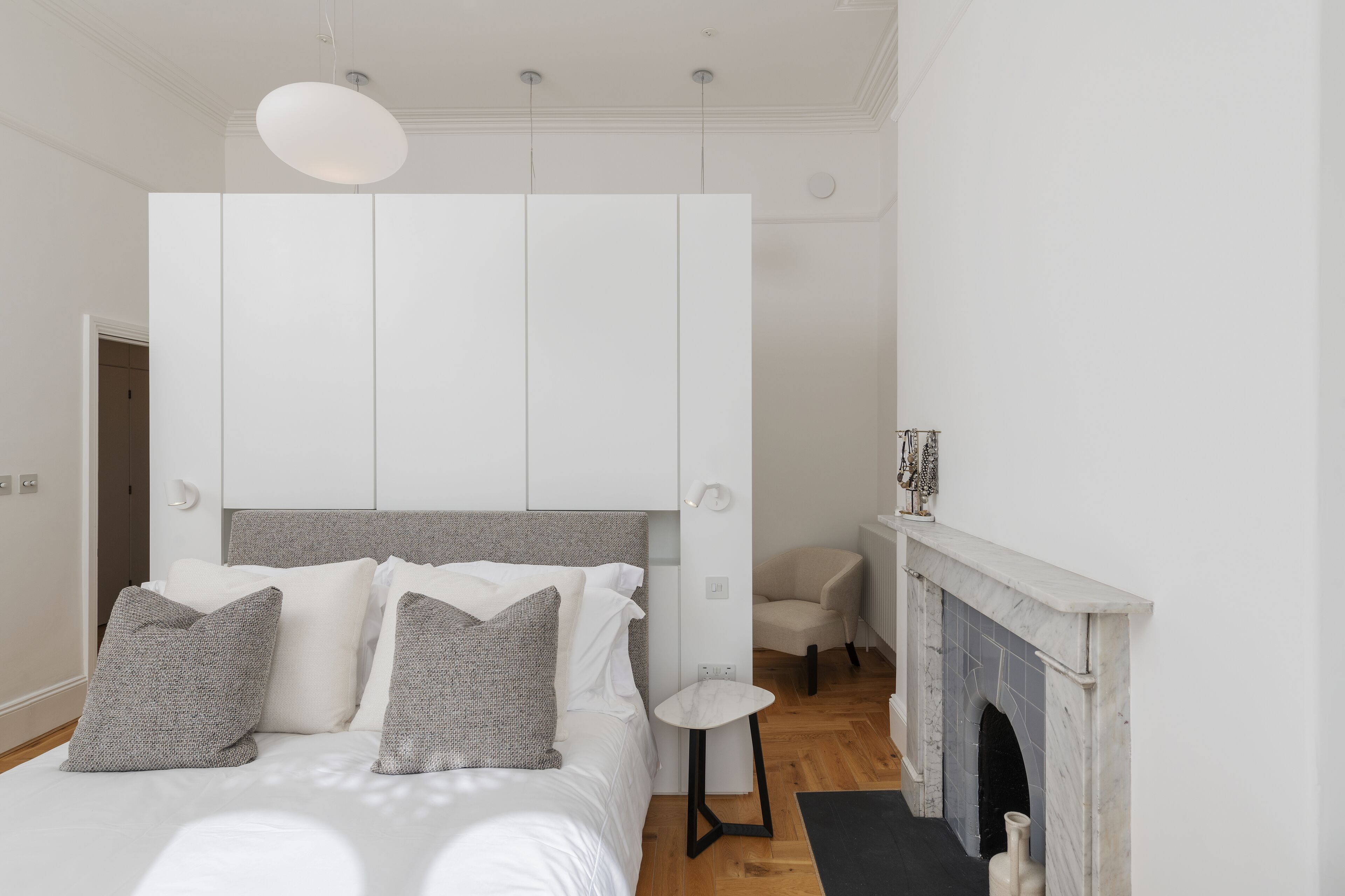 Um quarto moderno com uma cama grande, uma mesinha de cabeceira, uma lareira e uma cadeira.