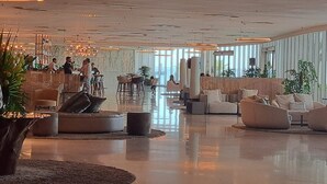 Um hall amplo com mobiliário moderno, janelas grandes e piso lustroso.