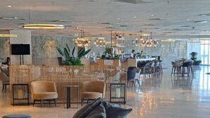 Um lobby moderno com área de estar circular, balcão de recepção e bar.
