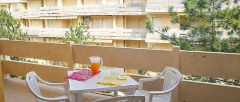 Terraço com mesa e cadeiras, um jarro de suco de laranja e um guardanapo cor-de-rosa.